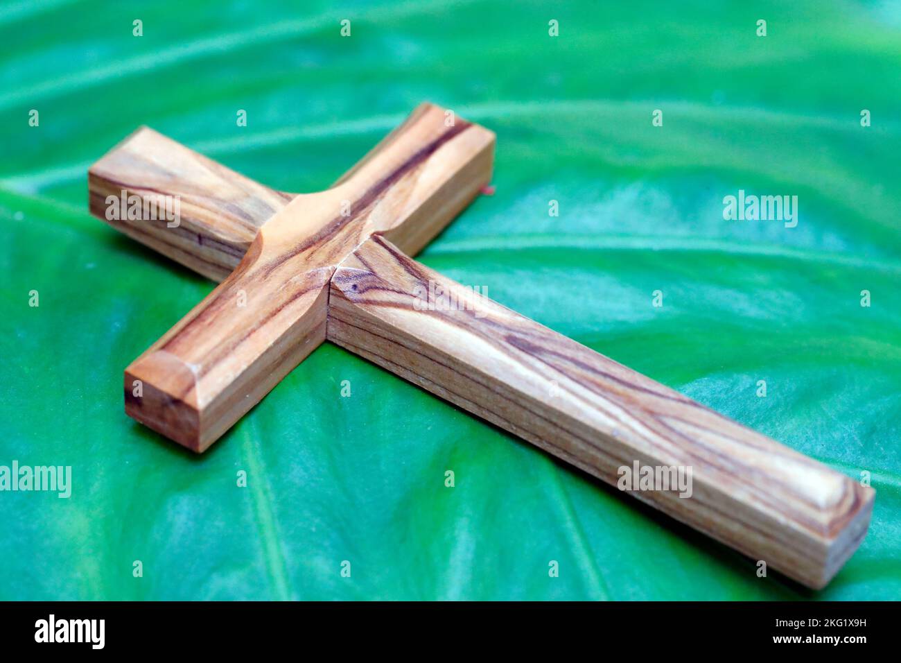 A wooden christian cross on a green leave. Symbol of christianity Stock ...