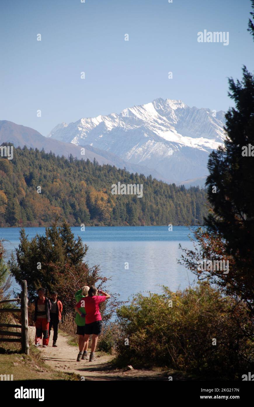 two women trekkers stand on the lakeside path in rara lake national ...