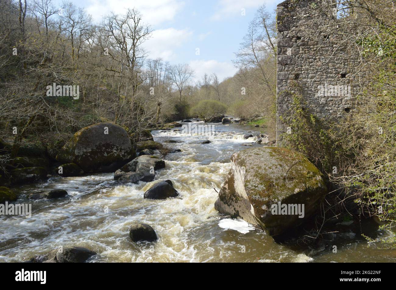 A river flowing in the countryside with trees and an abandoned old ...