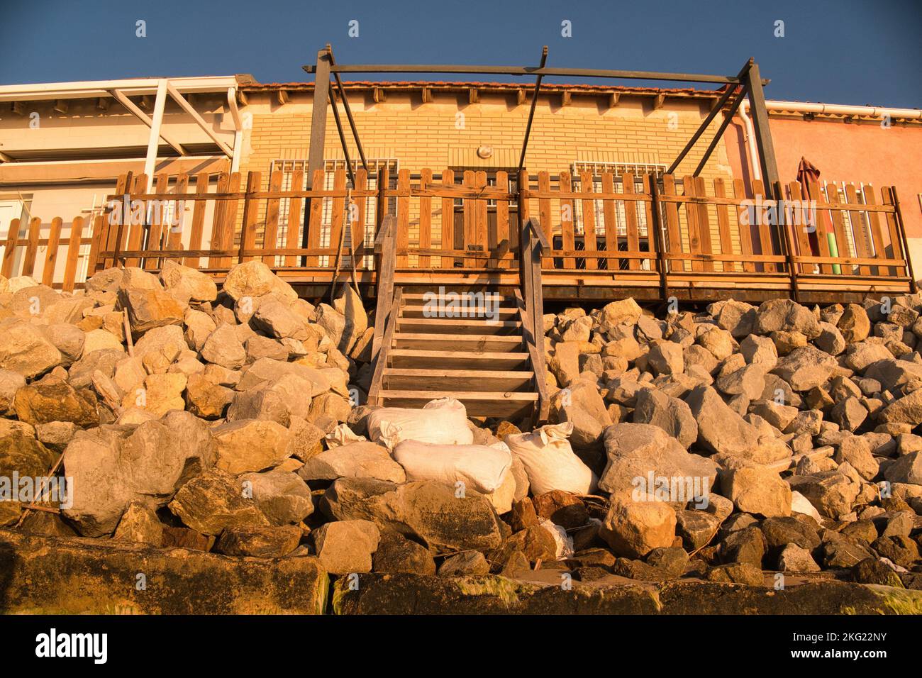 An exterior shot of an old stone house with rocks on a sandy beach at ...