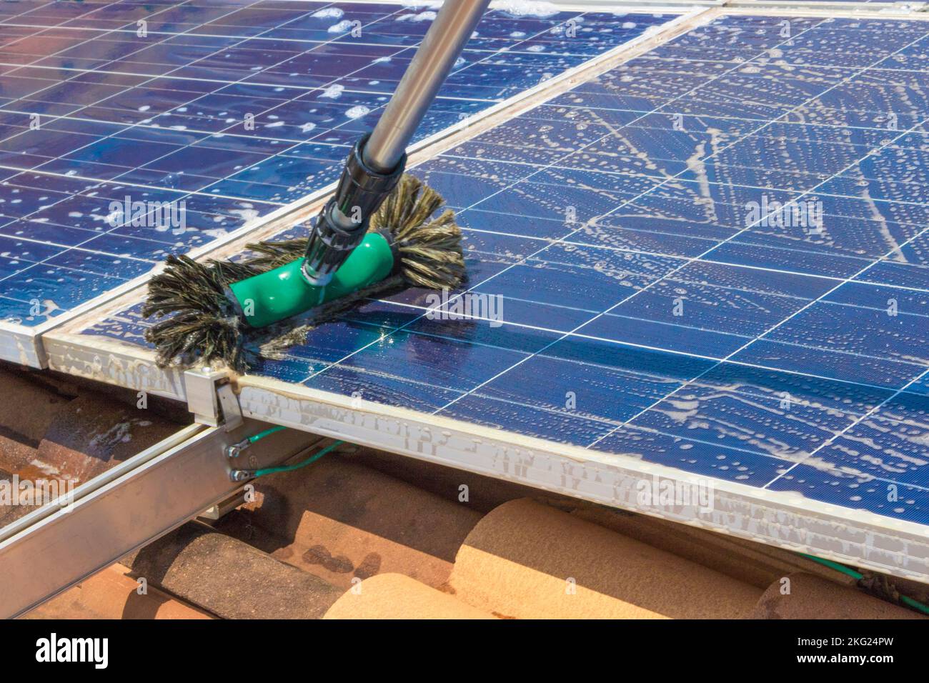 Solar worker cleaning photovoltaic panels with brush and water ...