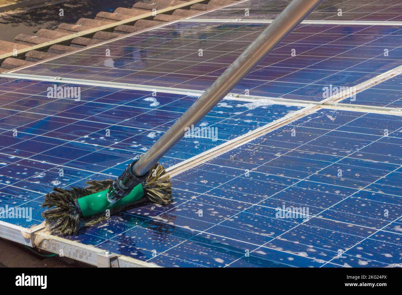Solar worker cleaning photovoltaic panels with brush and water ...