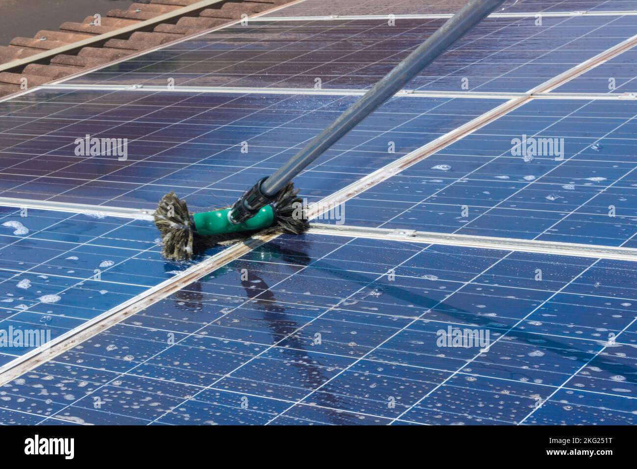 Solar worker cleaning photovoltaic panels with brush and water ...