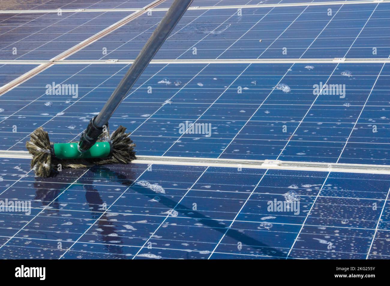 Solar worker cleaning photovoltaic panels with brush and water ...
