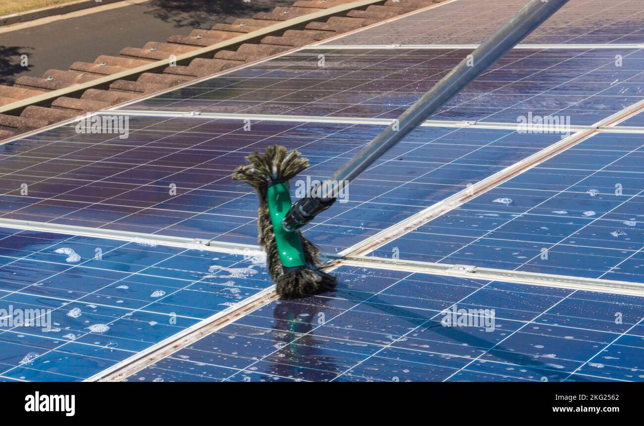 Solar worker cleaning photovoltaic panels with brush and water ...