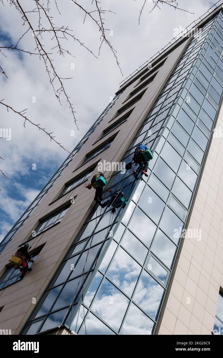 Three workers washing windows of the modern building. Men washing ...