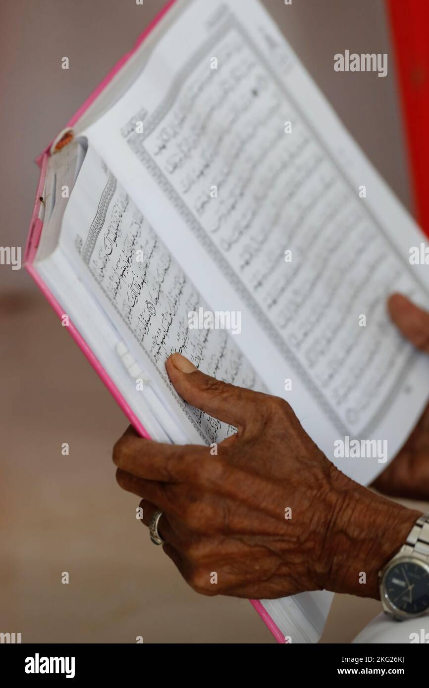 Masjid Ar-Rohmah mosque. Muslim man reading the arabic Holy Quran in ...