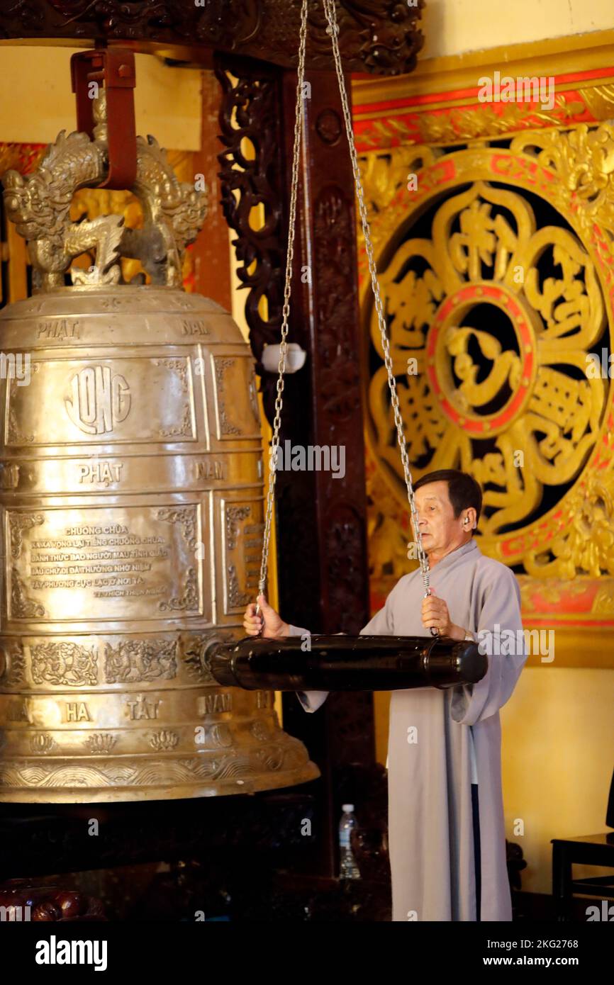 Long Duc buddhist temple. Buddhist monk ringing bell in monastery. Tan ...