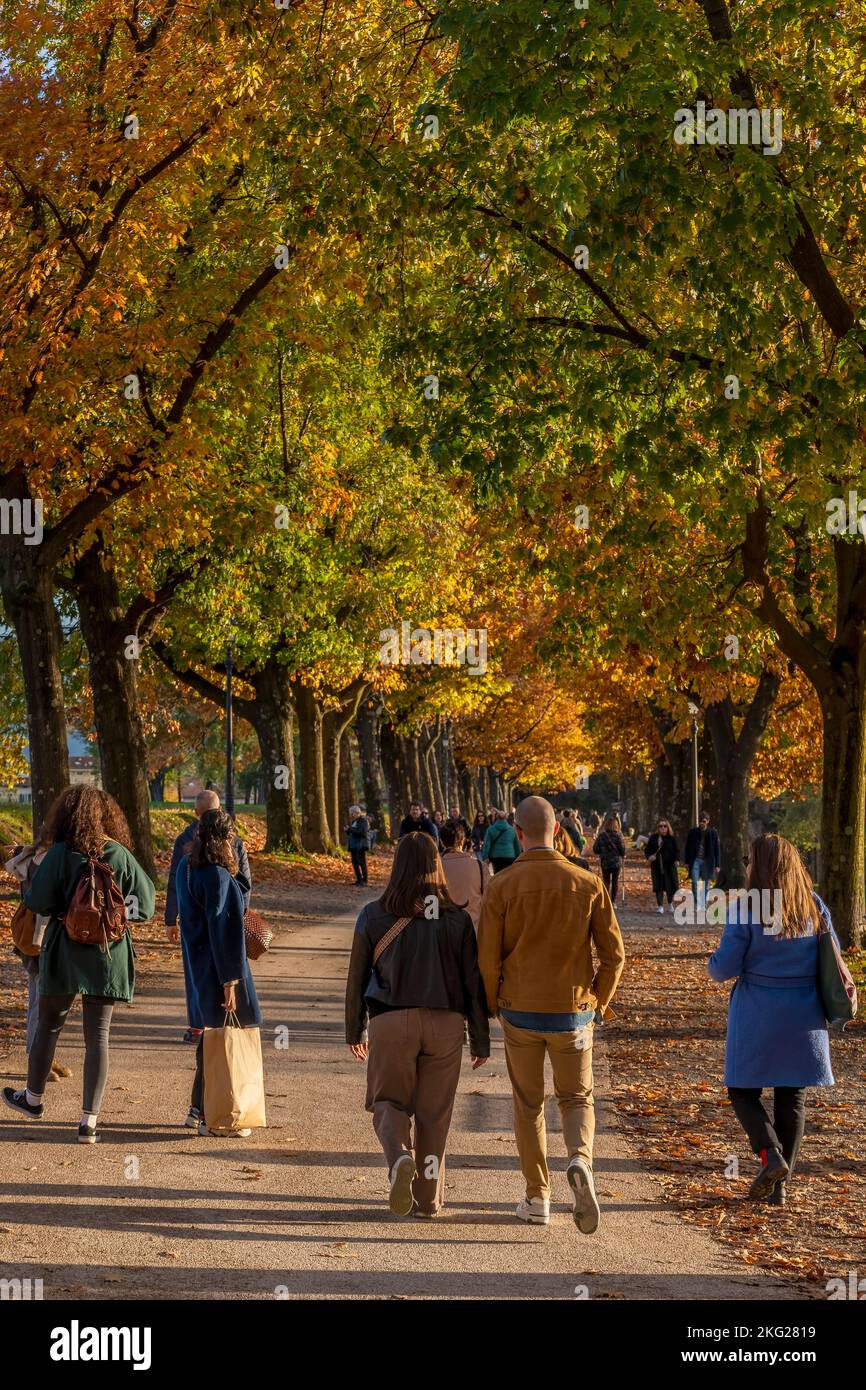 People walk on the ancient perimeter walls of Lucca, Italy, under a ...