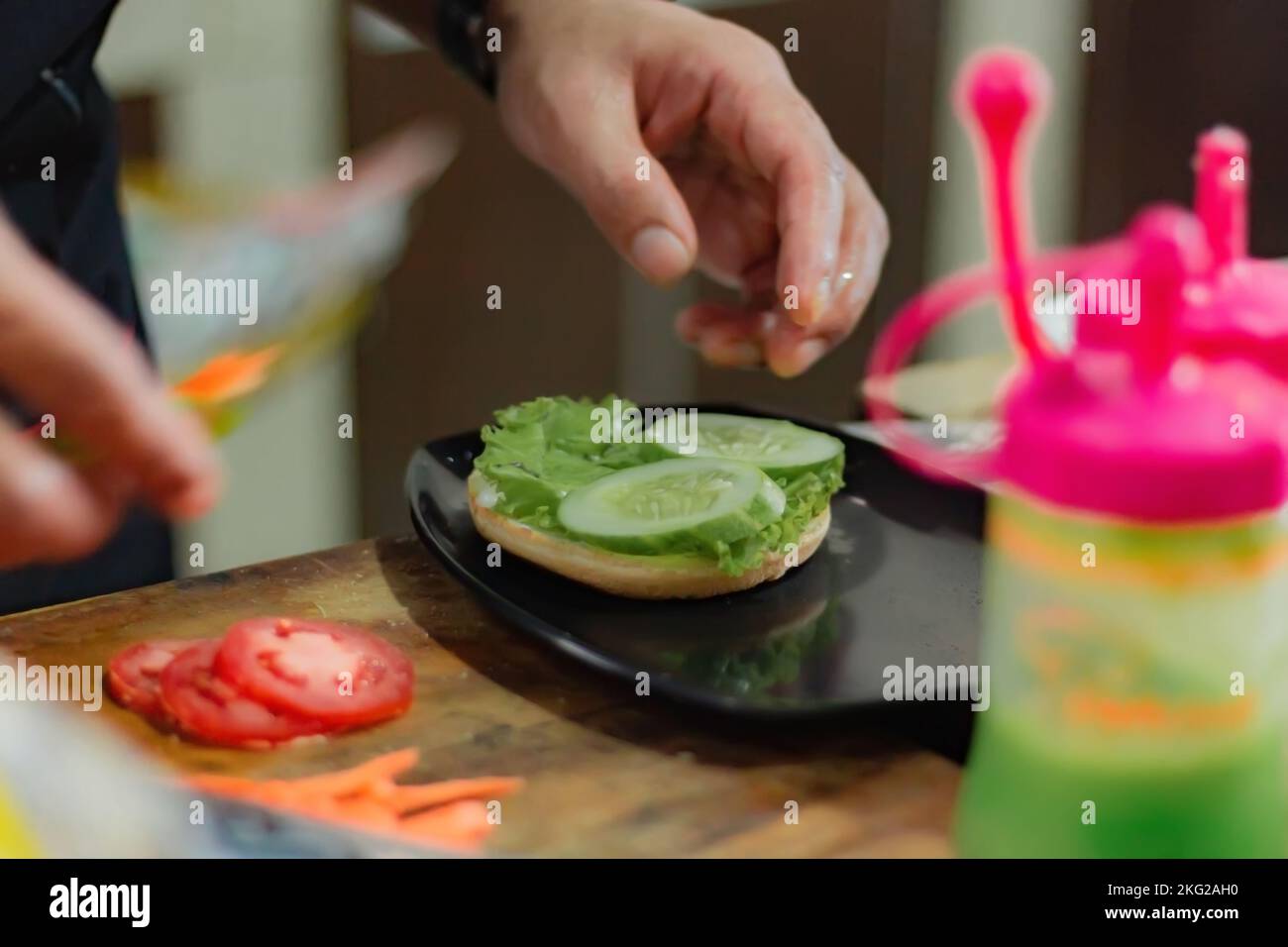 Chef puts tomato slice for burger filling, on kitchen utensils ...