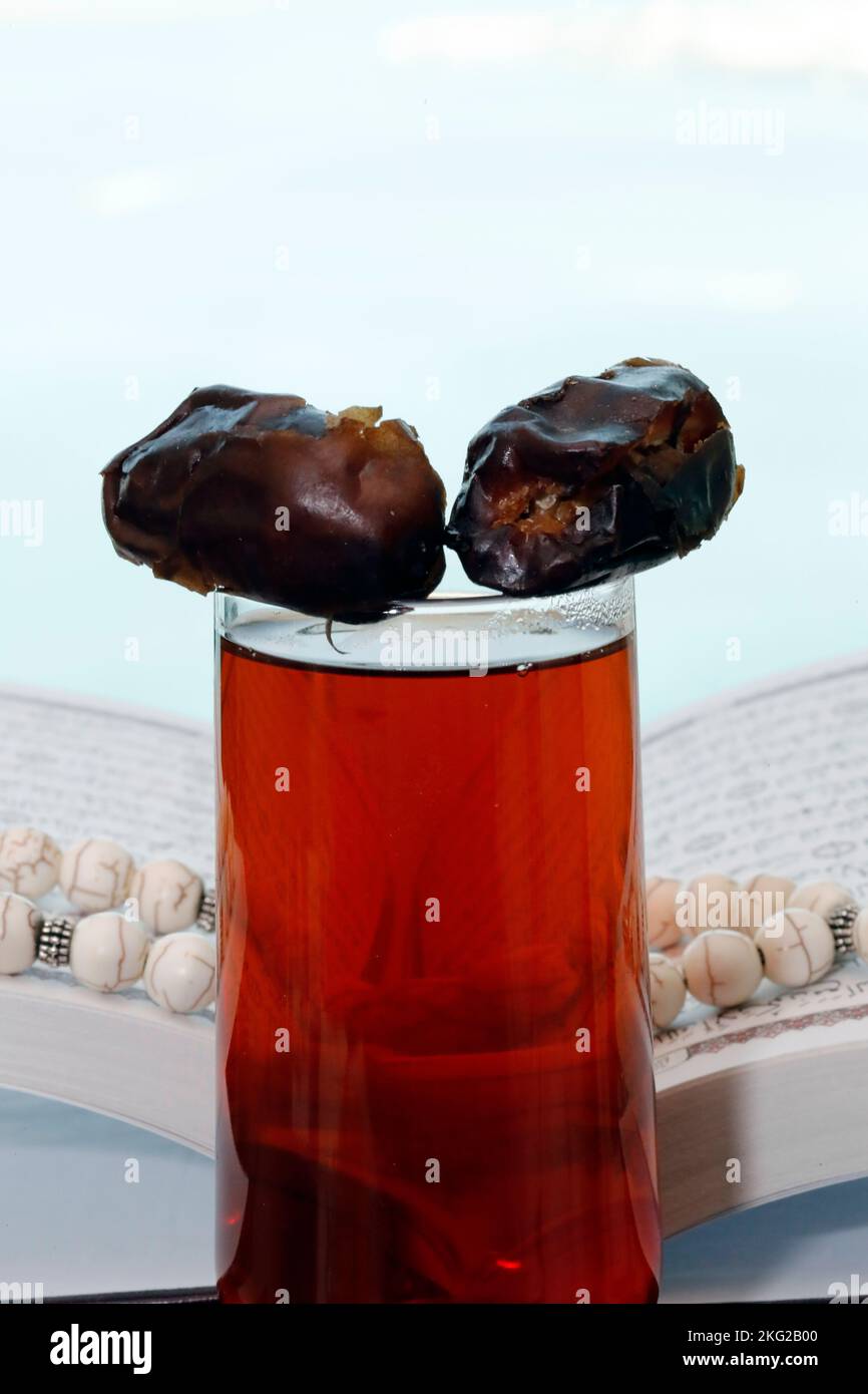 Holy Quran in arabic, muslim prayer beads, glass of tea and fresh dates ...