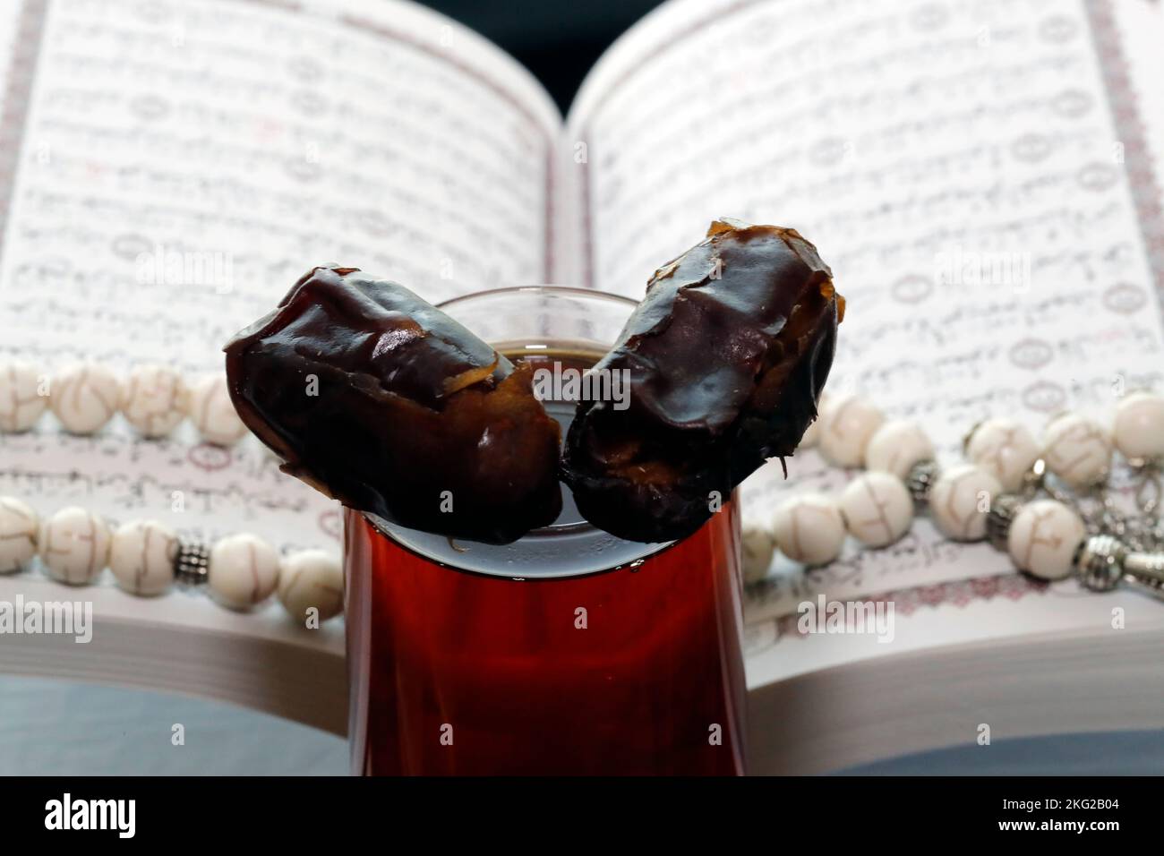 Holy Quran in arabic, muslim prayer beads, glass of tea and fresh dates ...