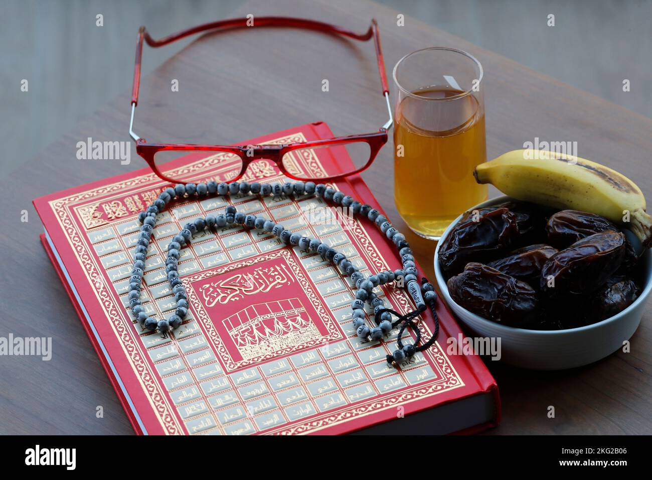 Holy Quran in arabic, muslim prayer beads, glass of tea and fresh dates ...