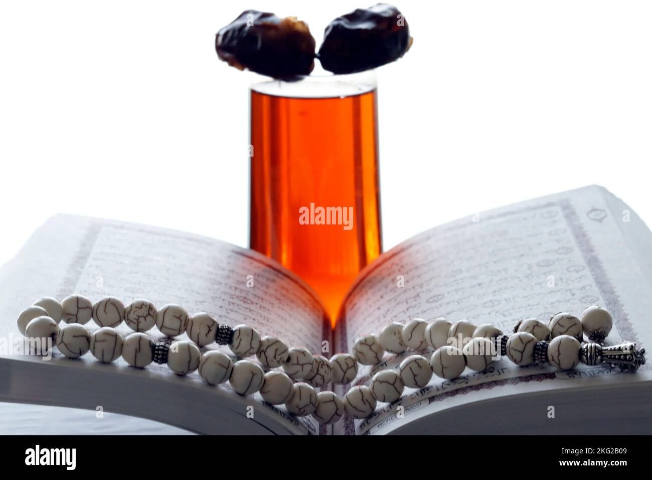 Holy Quran in arabic, muslim prayer beads, glass of tea and fresh dates ...