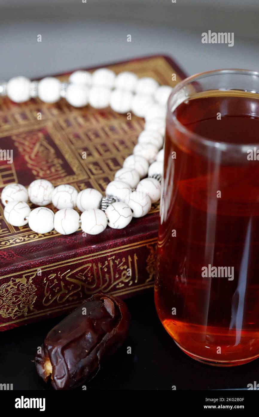 Holy Quran in arabic, muslim prayer beads, glass of tea and fresh date ...