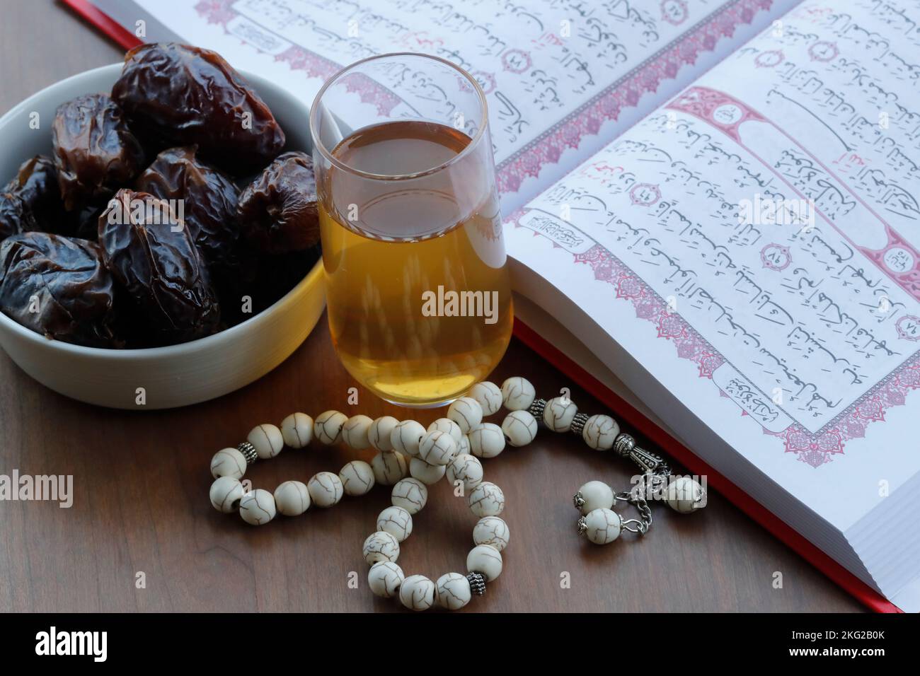 Holy Quran in arabic, muslim prayer beads, glass of tea and fresh dates ...