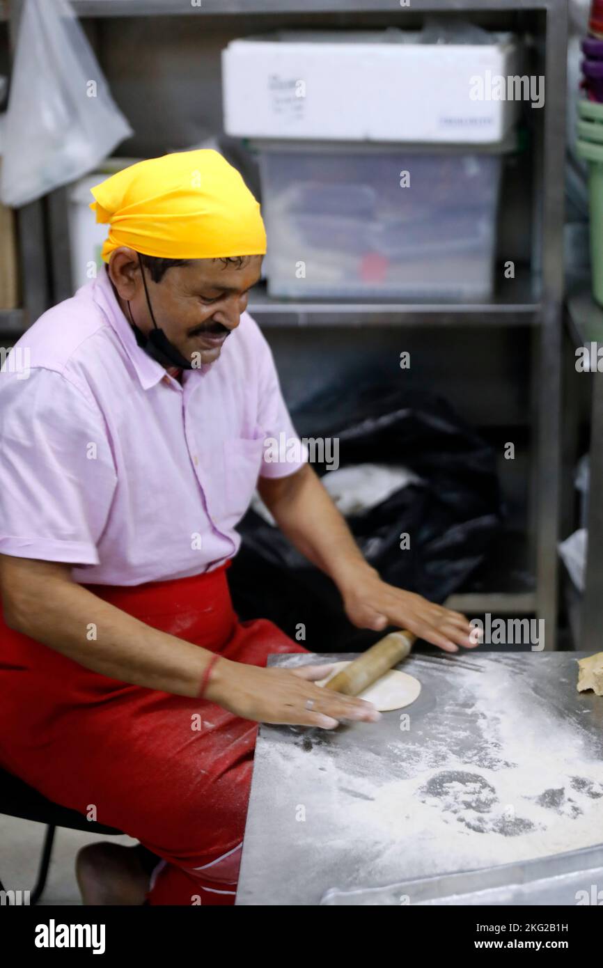 Hindu man preparing indian flat bread Chapathi from wheat dough. Shiva ...