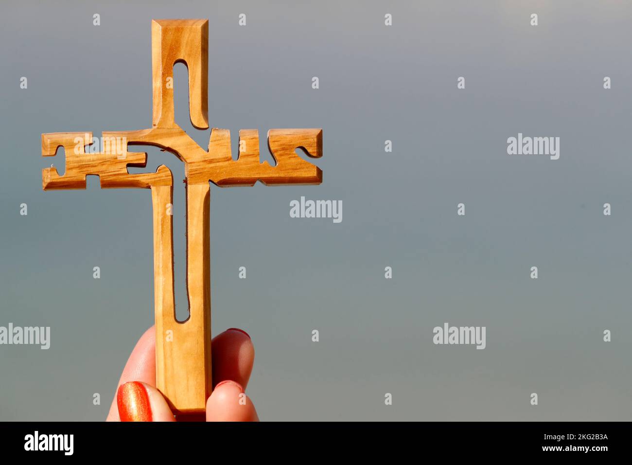 Christian woman holding a christian cross with the name of Jesus. Close up on hands. Concept for ...