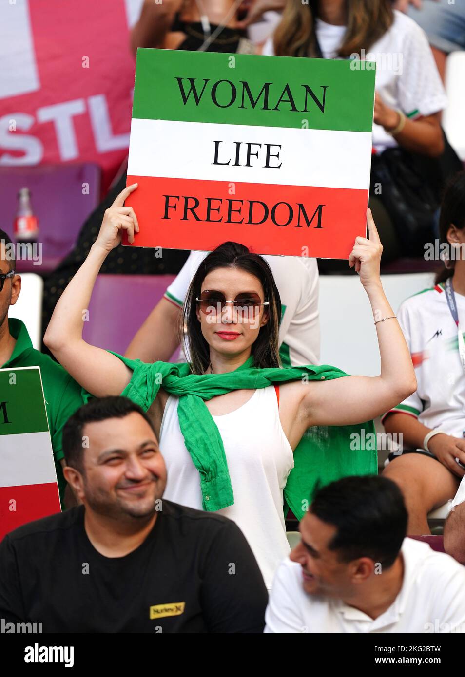 An Iran fan in the stands holds up a sign reading "Woman Life Freedom ...