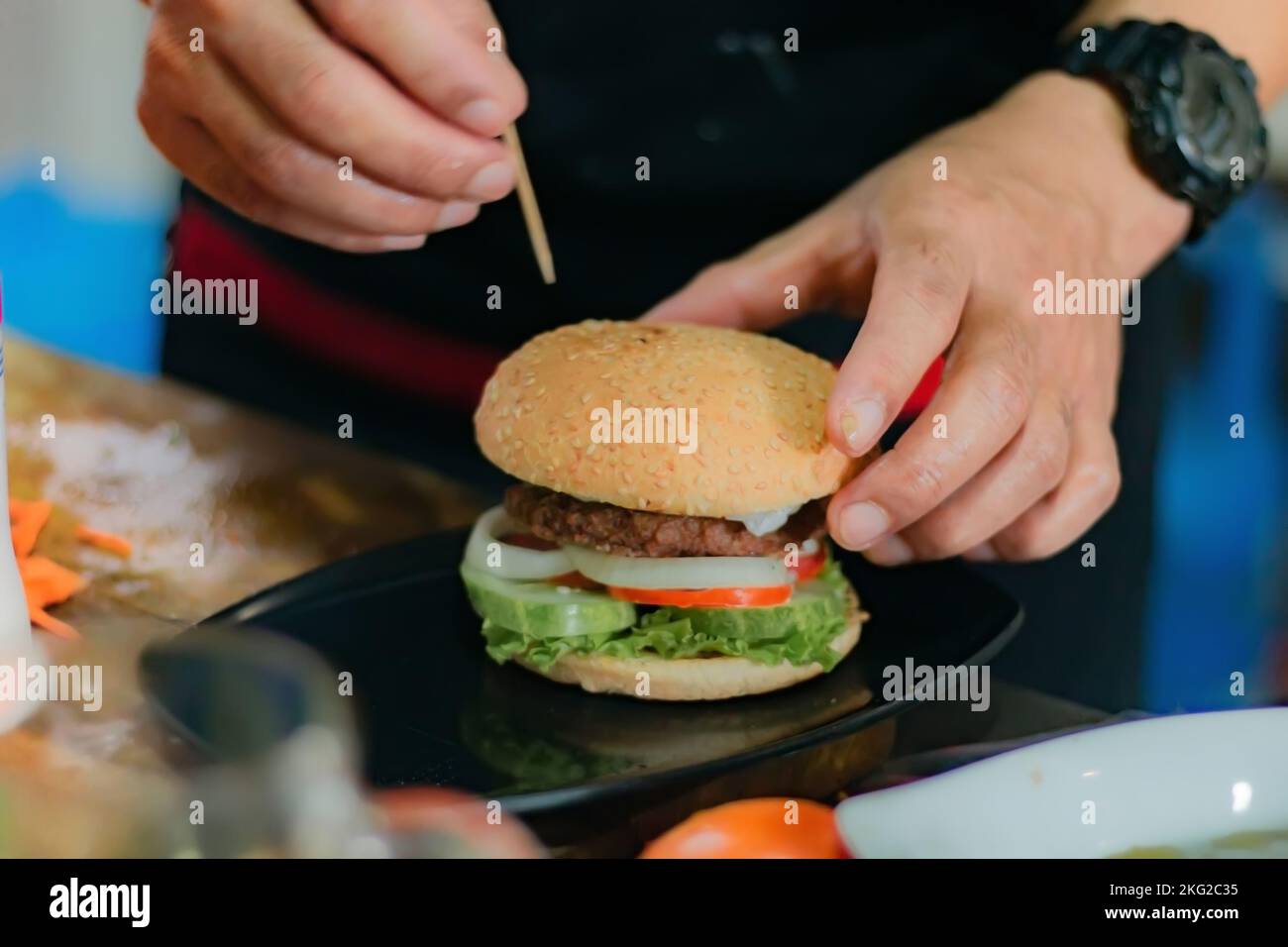 Chef ready to serve burger, on kitchen utensils background Stock Photo ...
