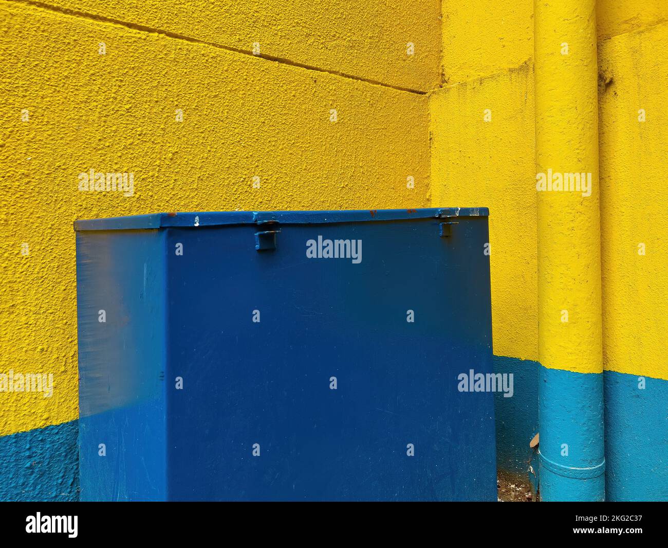 Blue metallic box container on the street against the wall in yellow ...