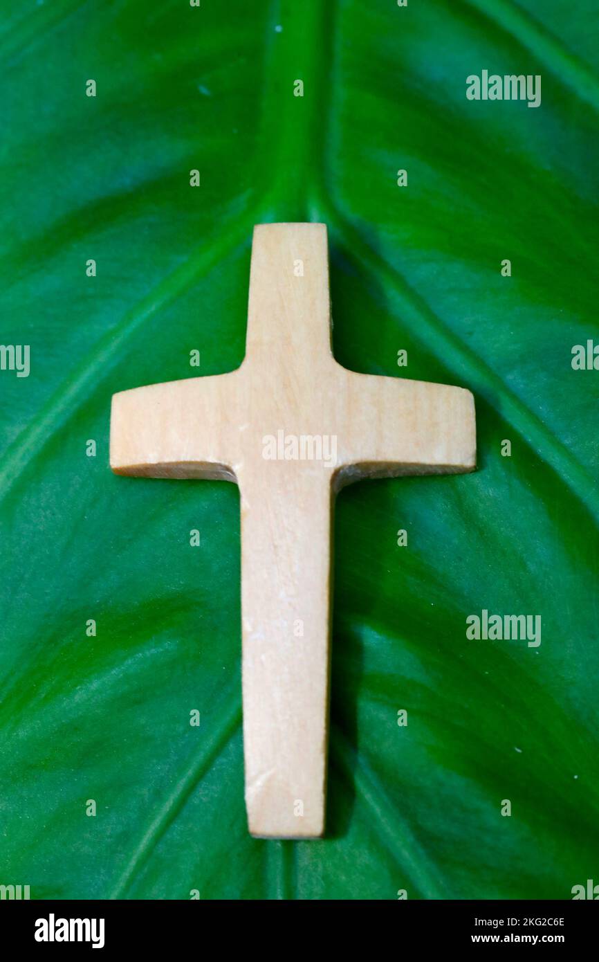 A wooden christian cross on a green leave. Symbol of christianity Stock ...