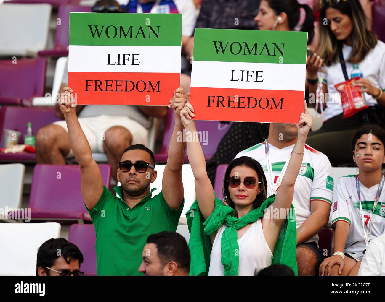 Iran fans in the stands hold up signs reading "Woman Life Freedom ...