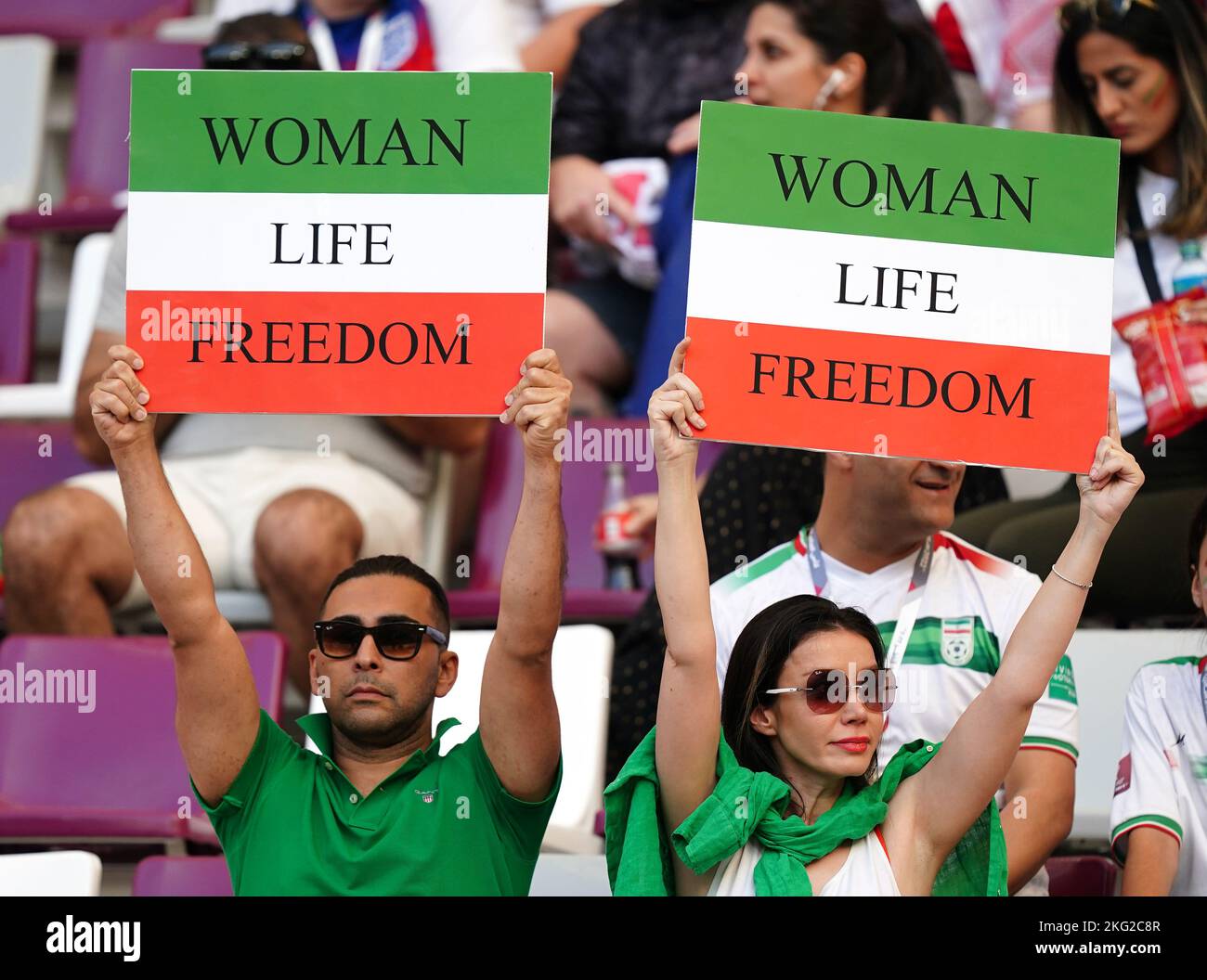 Iran fans in the stands hold up signs reading "Woman Life Freedom ...