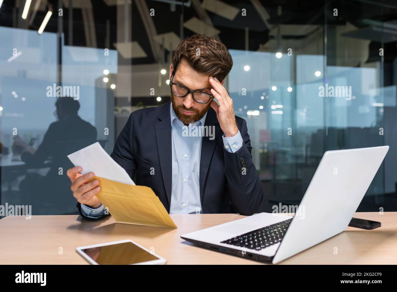 Sad and upset mature businessman received an envelope by mail with a ...