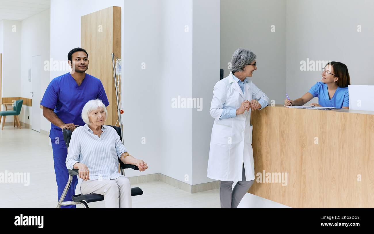 Healthcare assistant pushes wheelchair with senior woman in motion ...