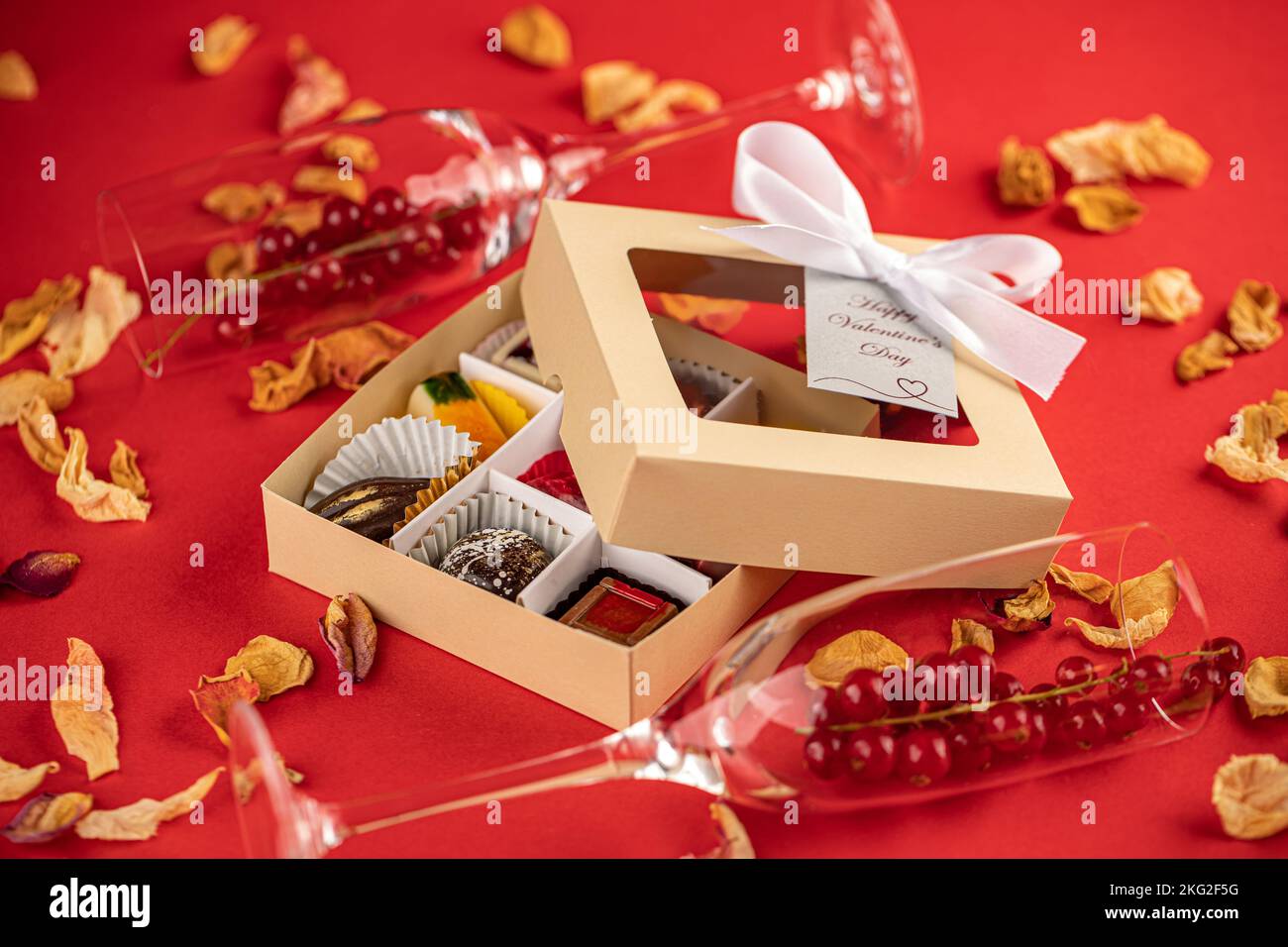 A box of Valentine's chocolate candies and two glasses of red berries ...