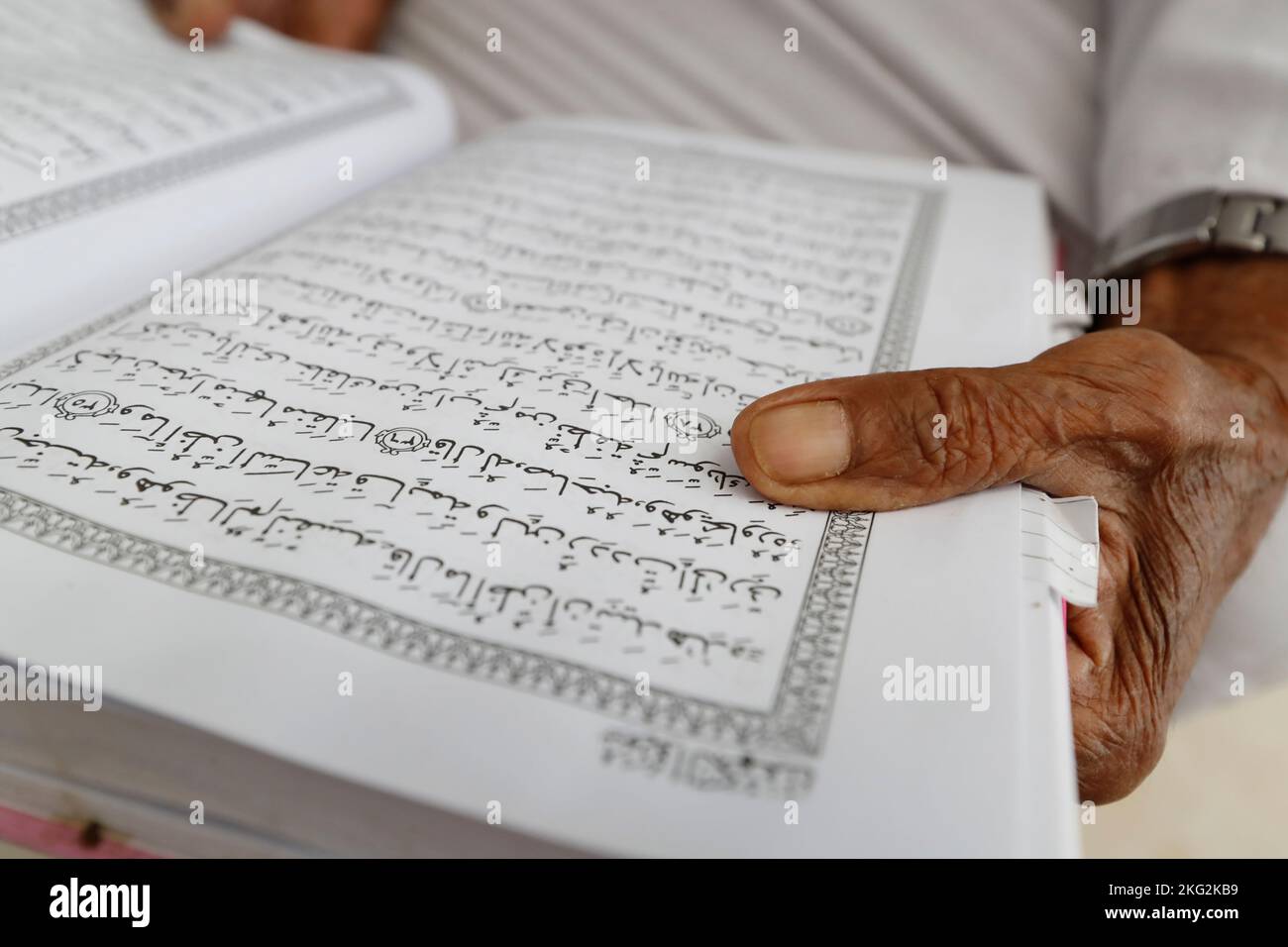 Masjid Ar-Rohmah mosque. Muslim man reading the arabic Holy Quran in ...