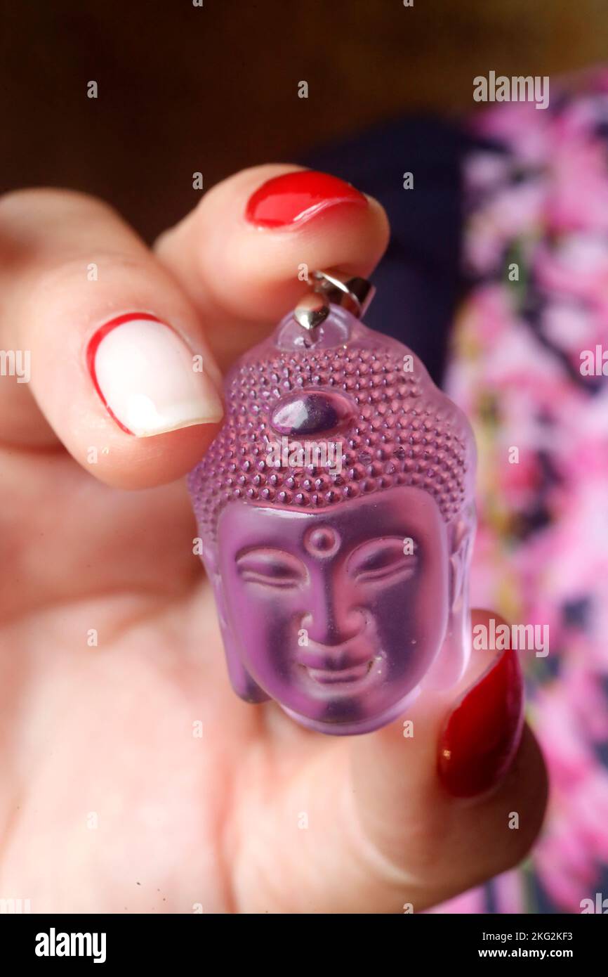 Pink Buddha head pendant in hand. Buddhist symbol Stock Photo - Alamy