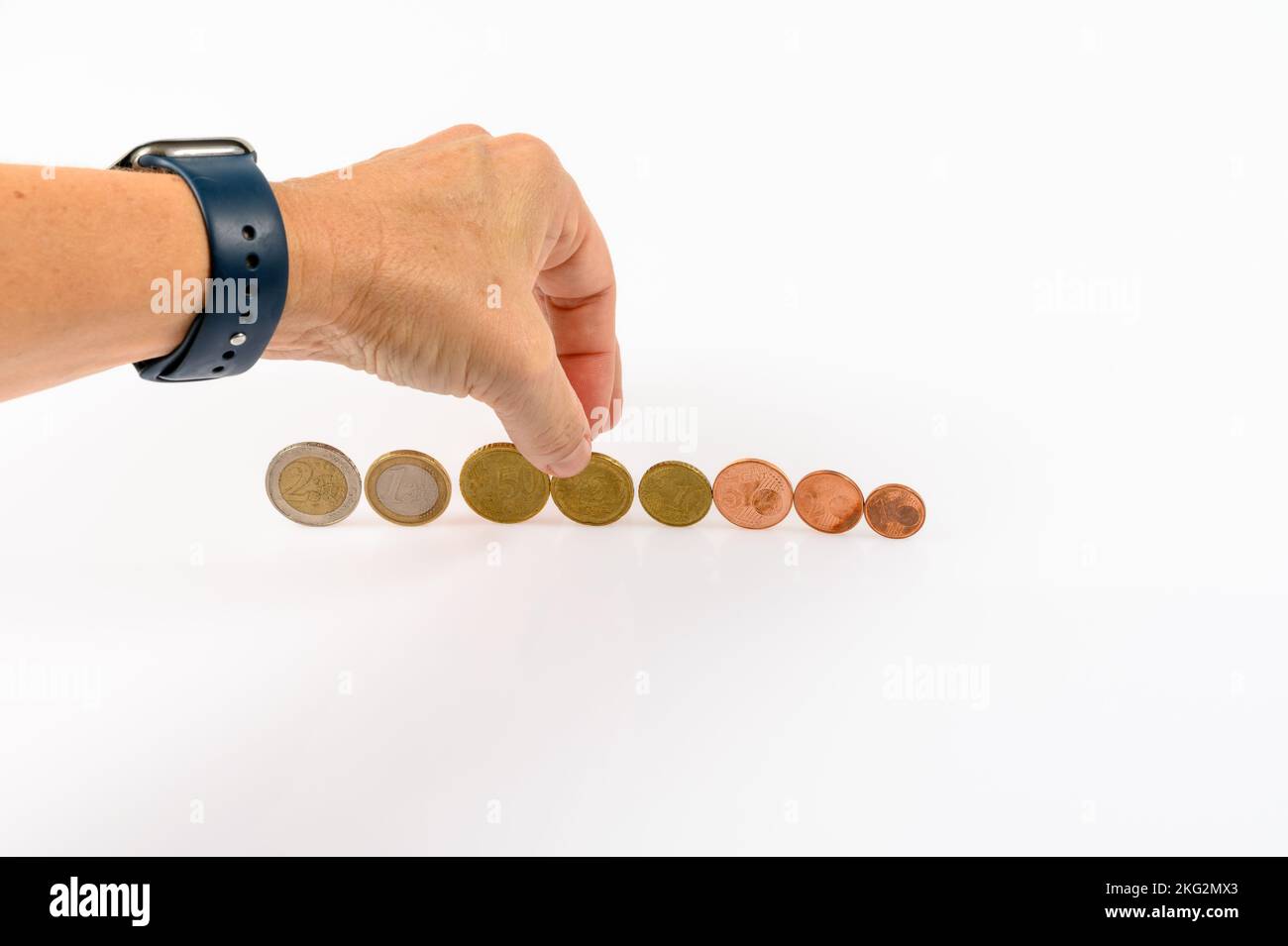 woman hand places complete set of euro coins upright on a white table ...