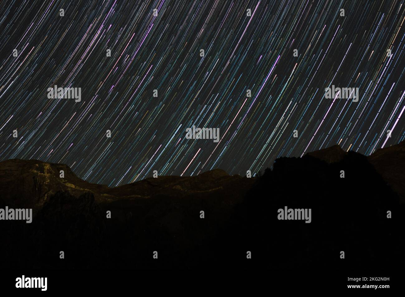 The star trails in the black night sky over the land silhouette, long ...