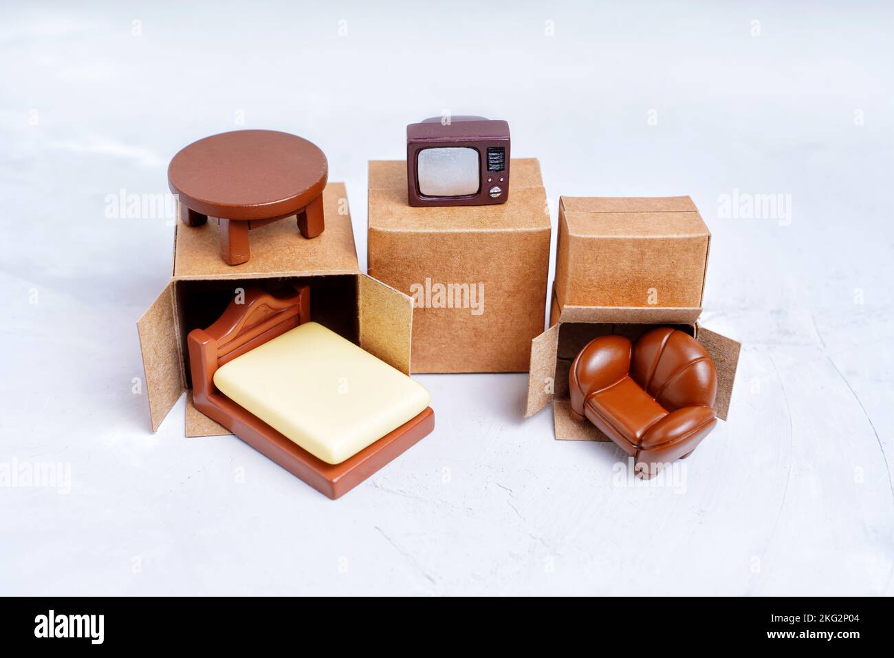 Tiny delivery boxes and miniature furniture figurines isolated on gray ...