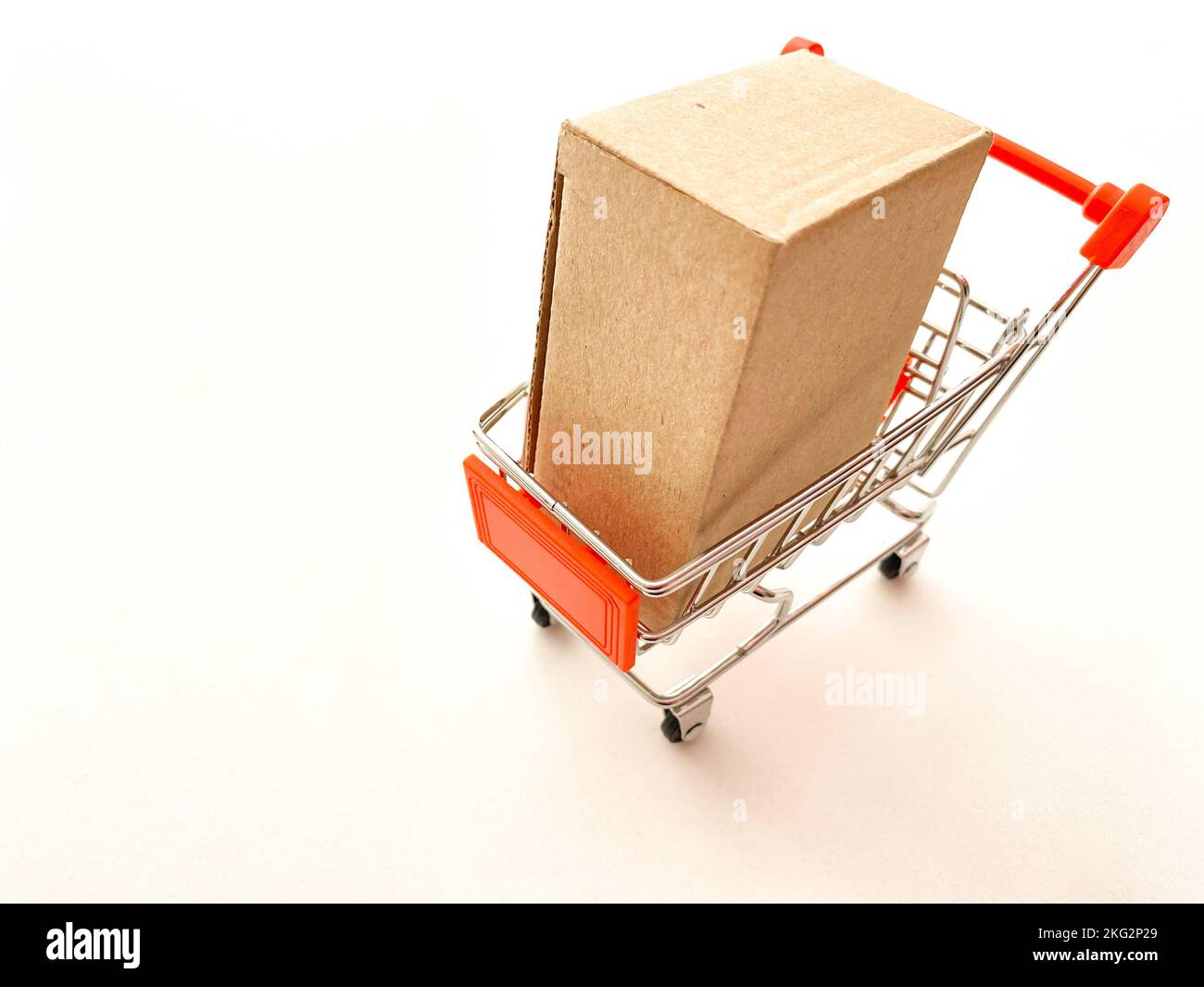 A mini shopping cart with a box isolated on a pink surface Stock Photo ...
