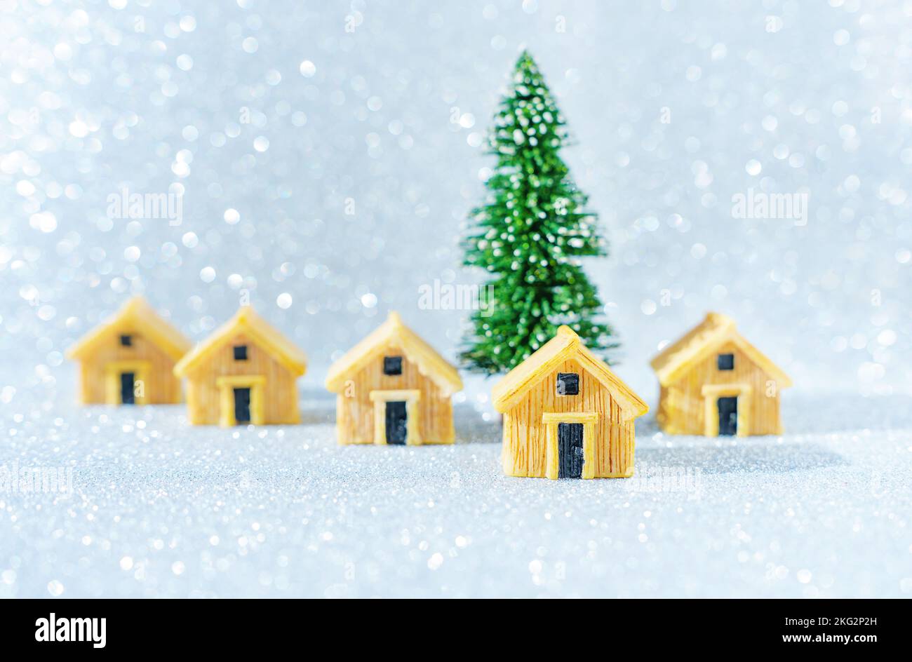 Group of tiny wooden houses placed around a toy Christmas tree against ...