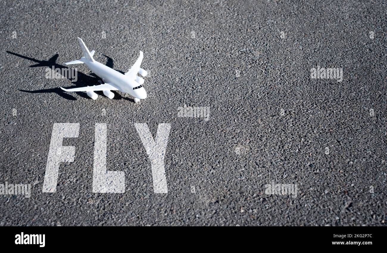 Model airplane and word FLY painted on the runway Stock Photo - Alamy
