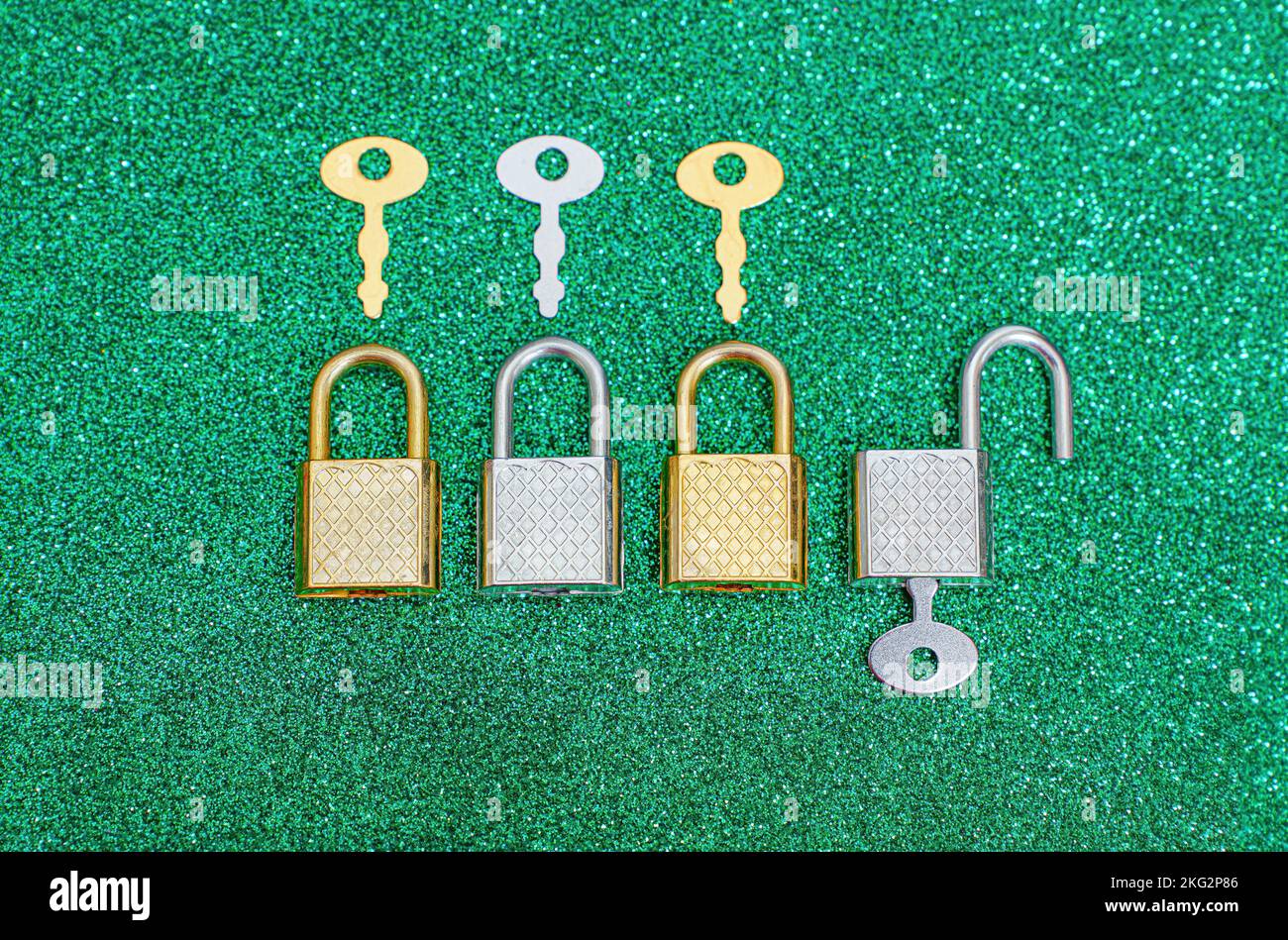 Row of four shiny metal padlocks and master keys isolated on a green ...