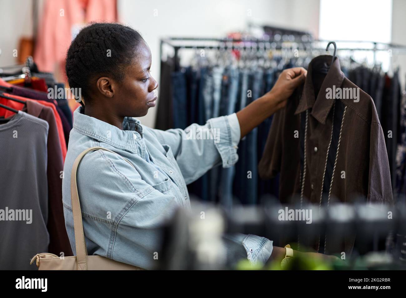 Side view portrait of black young woman looking at clothes in second ...
