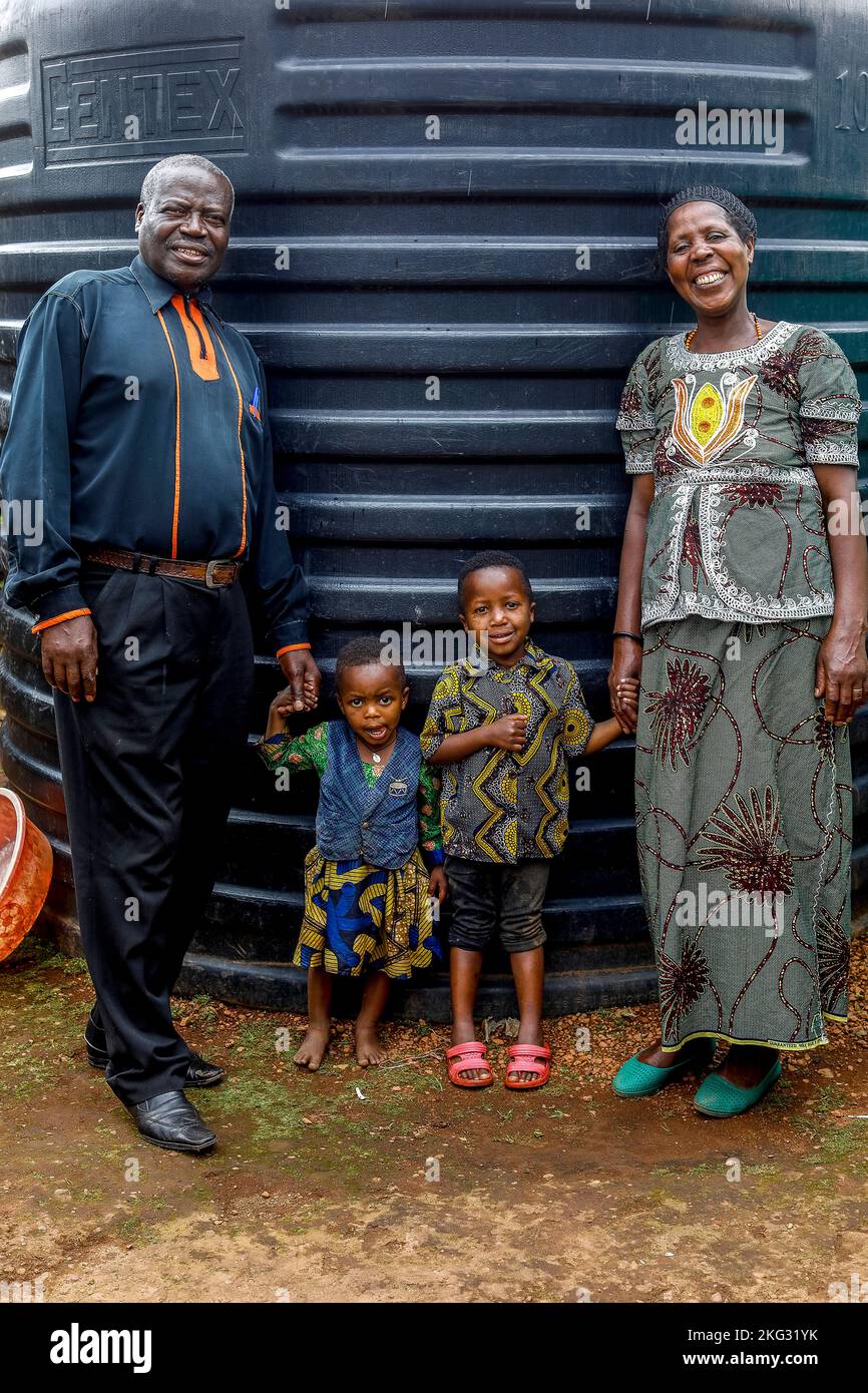 Grandparents and child near their water tank in a village near Gicumbi ...
