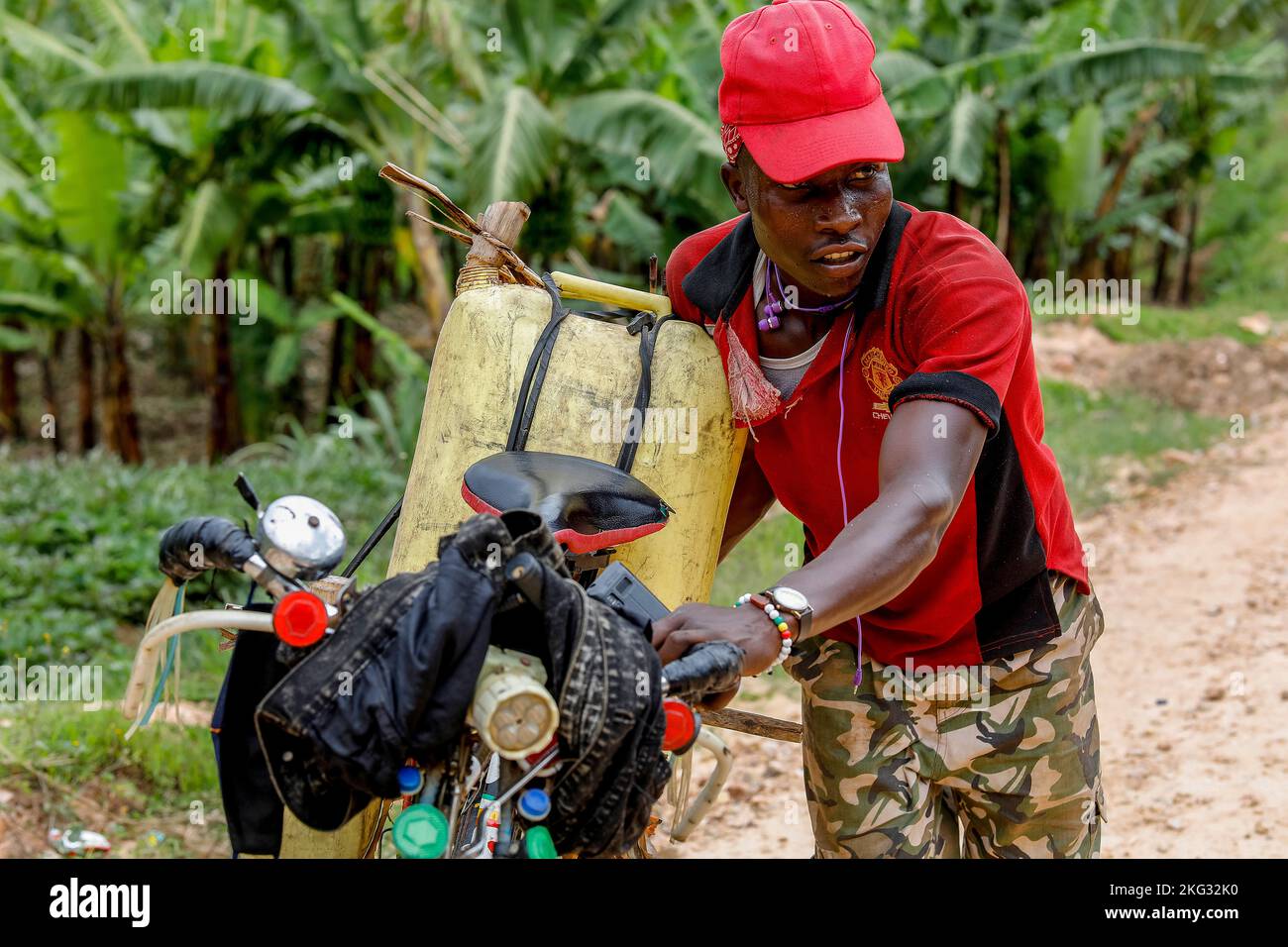 Man pushing a bike loaded with water tanks in western Rwanda Stock ...