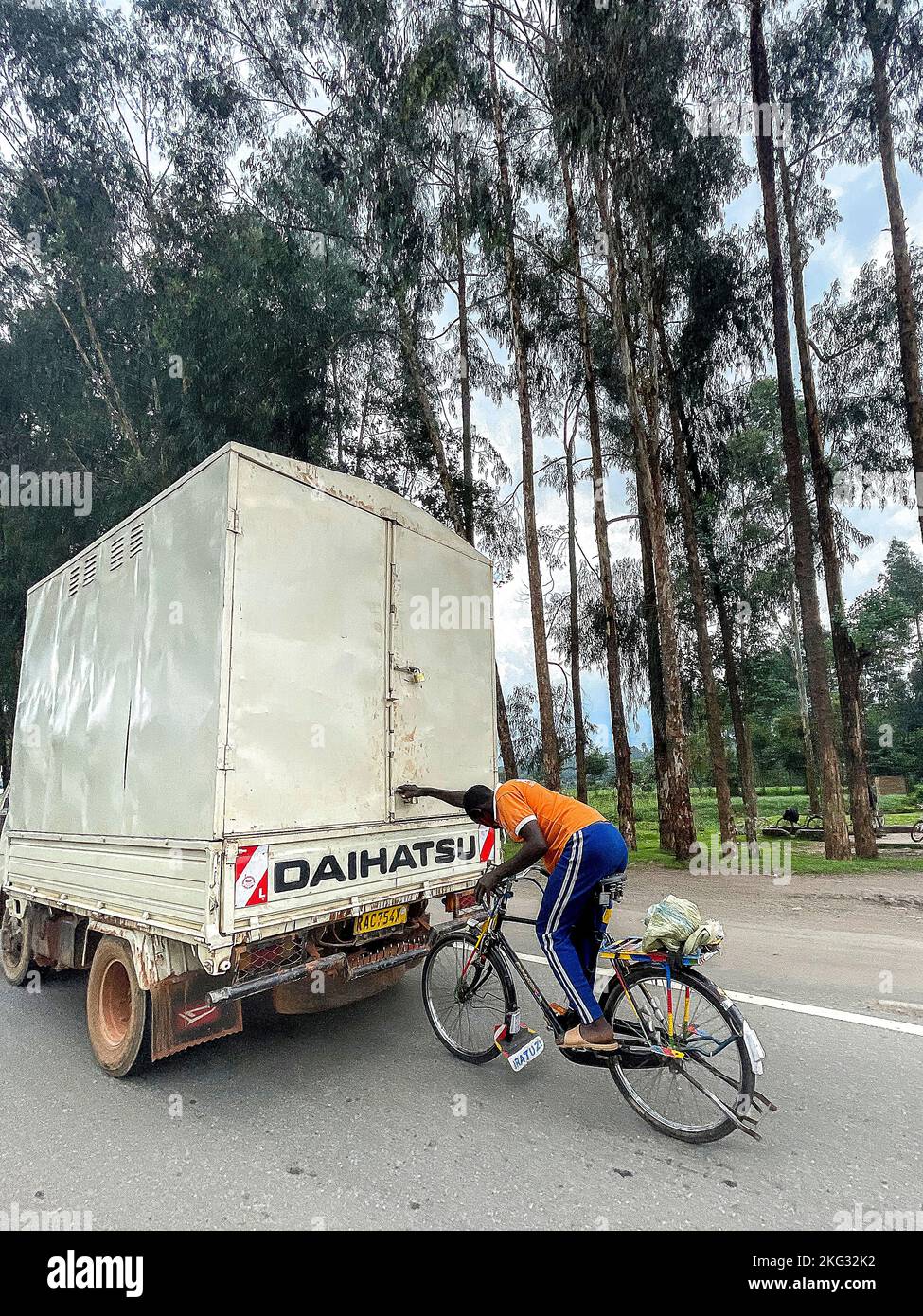Cyclist holding the back of a truck in Rwanda Stock Photo - Alamy