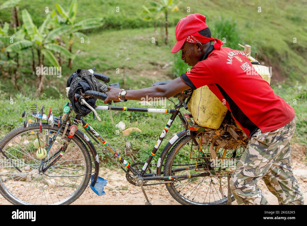 Man pushing a bike loaded with water tanks in western Rwanda Stock ...