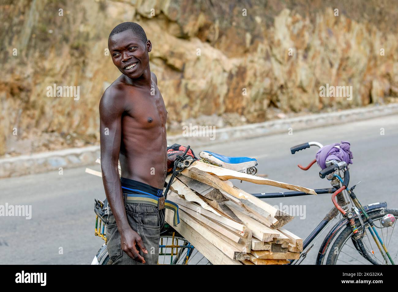 Young man pushing a bike loaded with planks in western Rwanda Stock ...