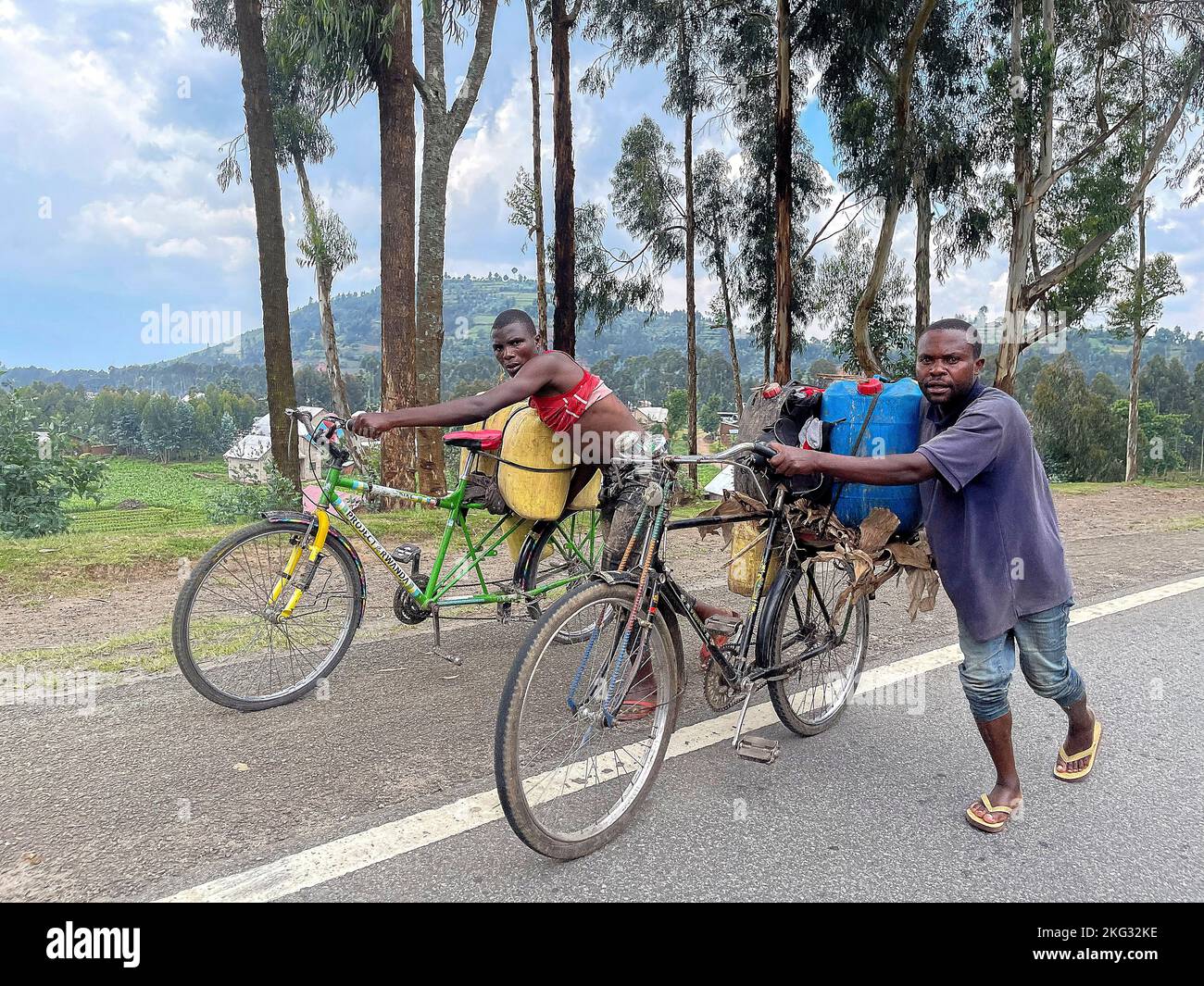 Cyclists pushing bikes loaded with water tanks in Rwanda Stock Photo ...