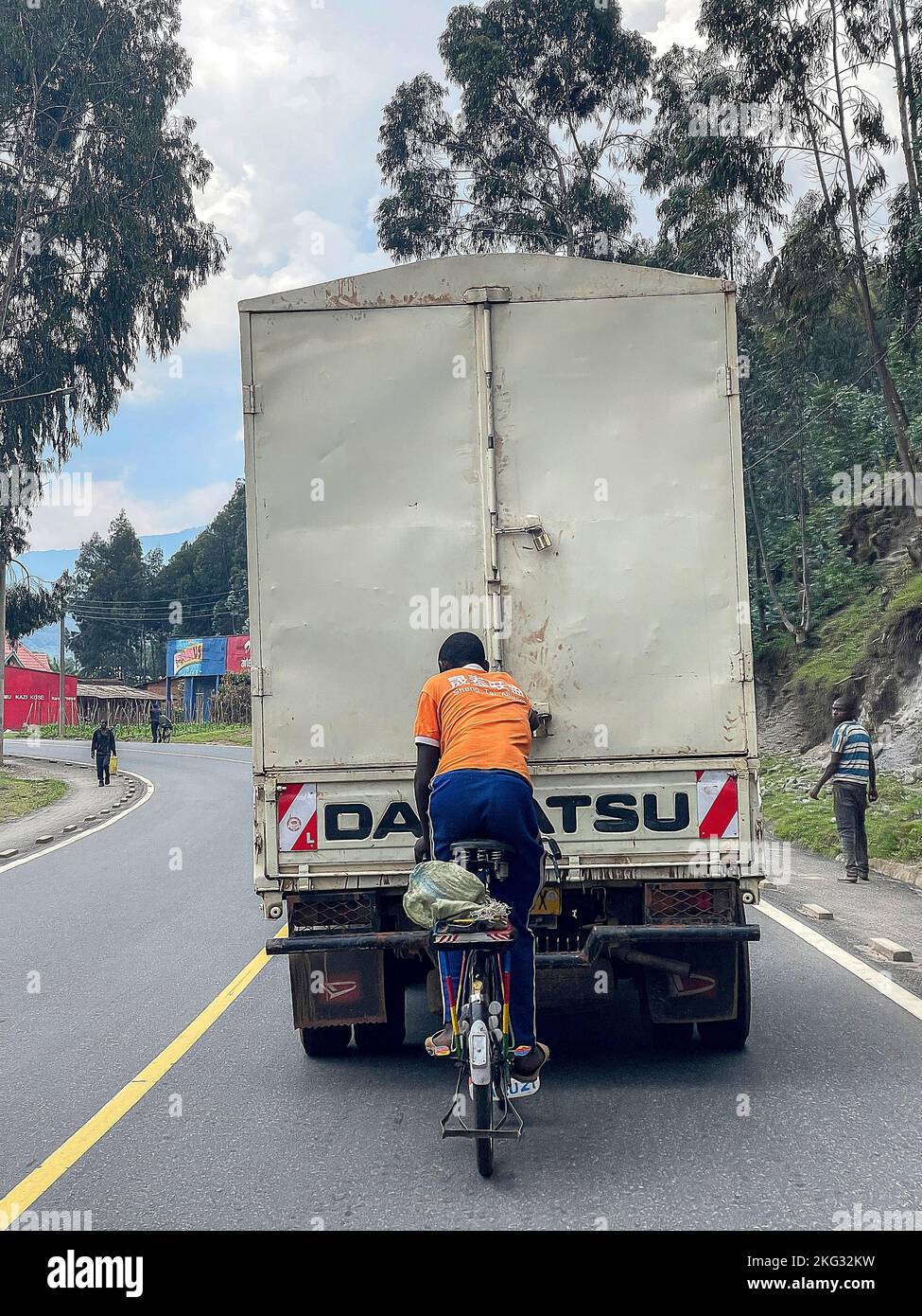 Cyclist holding the back of a truck in Rwanda Stock Photo - Alamy