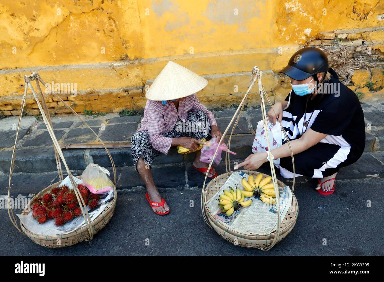 Typical street vendor with vietnamese hat sitting down selling food ...