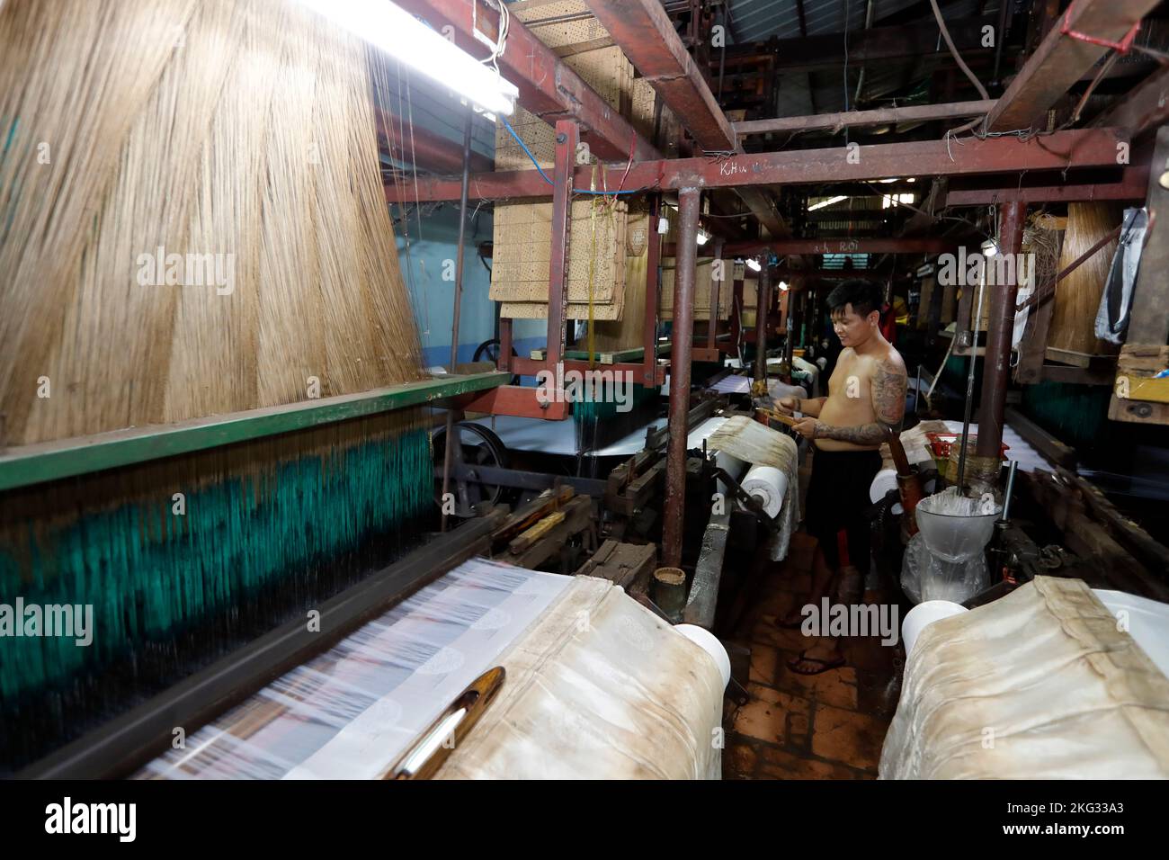 A traditional silk factory. Woman working on an old silk loom. Tan Chau ...